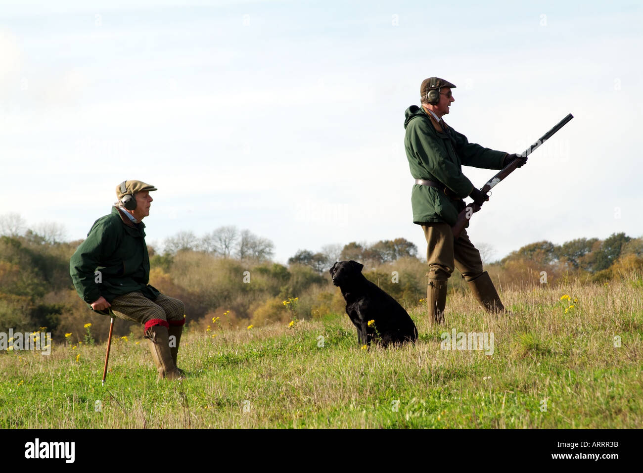 Shooting party member holding shotgun with his loader and black ...