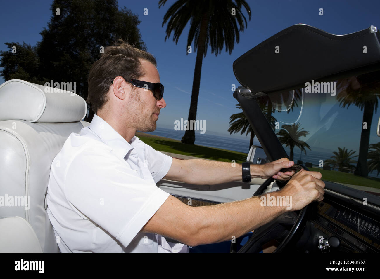 Side view of man driving car along beach Stock Photo - Alamy