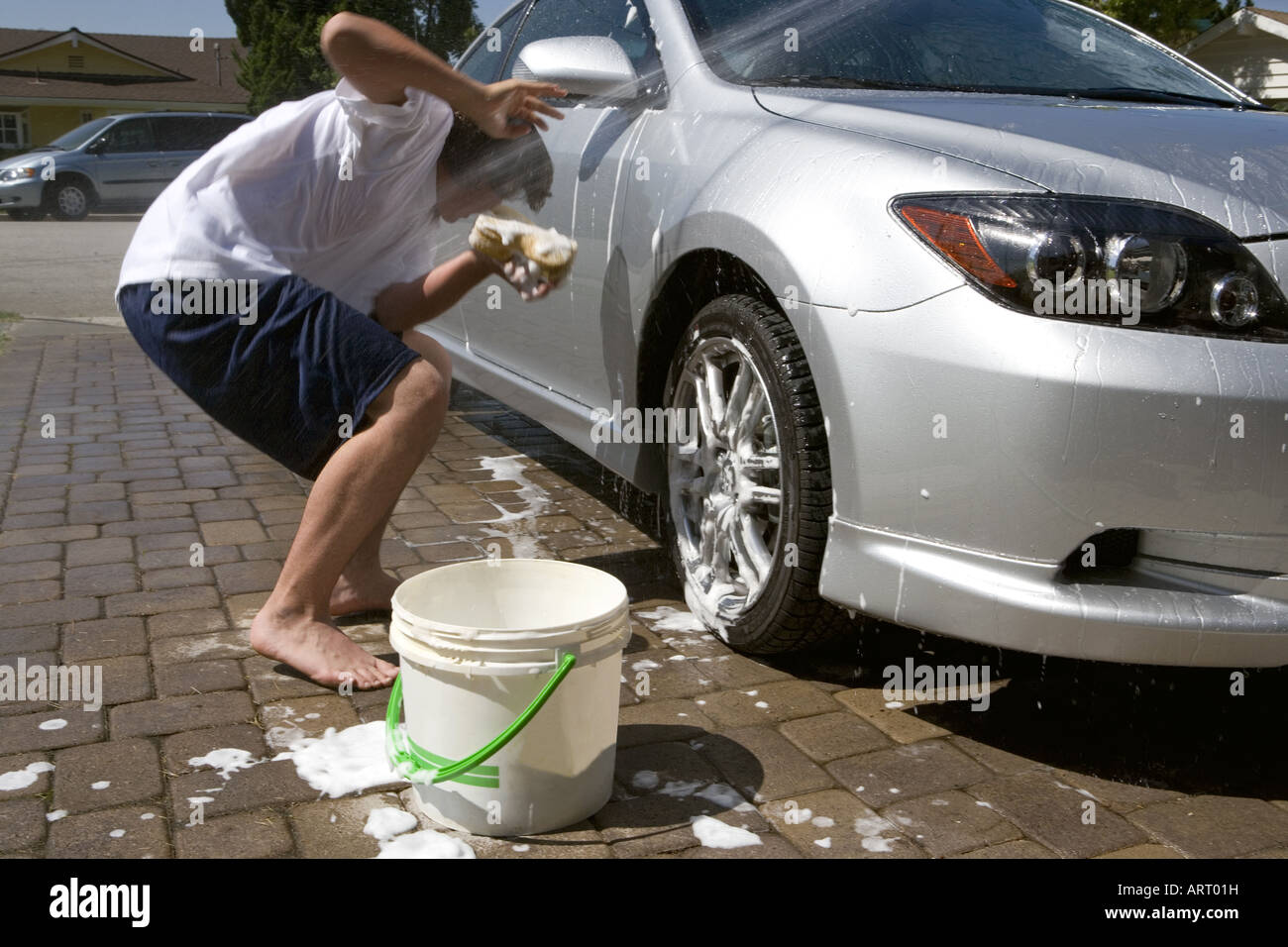 Teenage boy getting soaked while washing car Stock Photo - Alamy