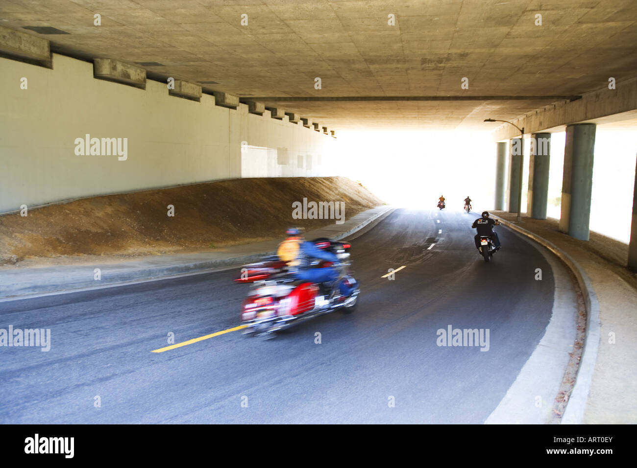 Motorcycles driving under train trestle Stock Photo - Alamy