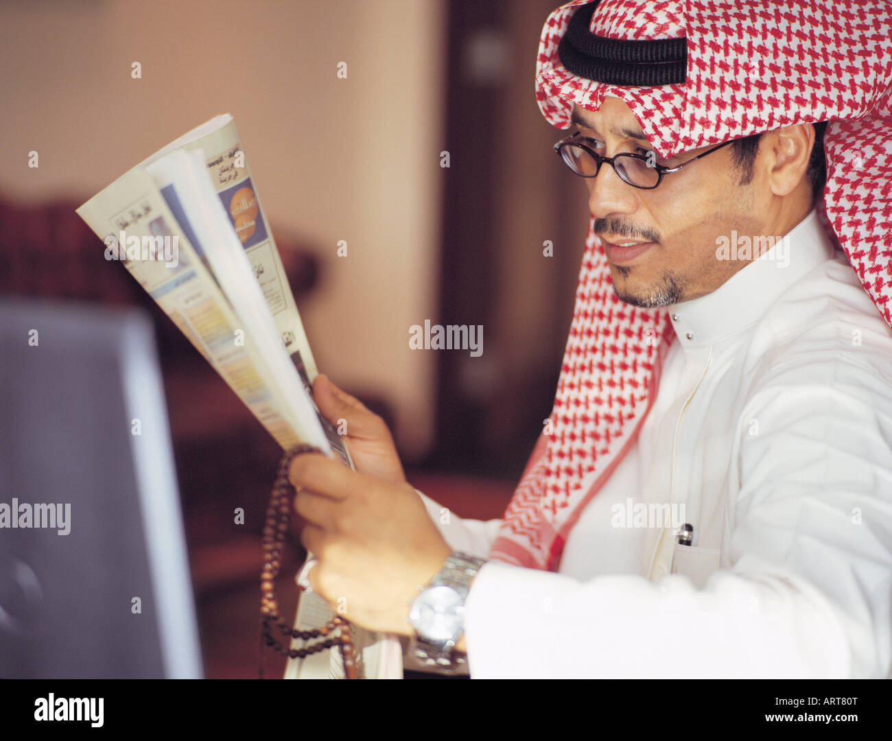 Saudi businessman reading Arabic newspaper and holding prayer beads ...