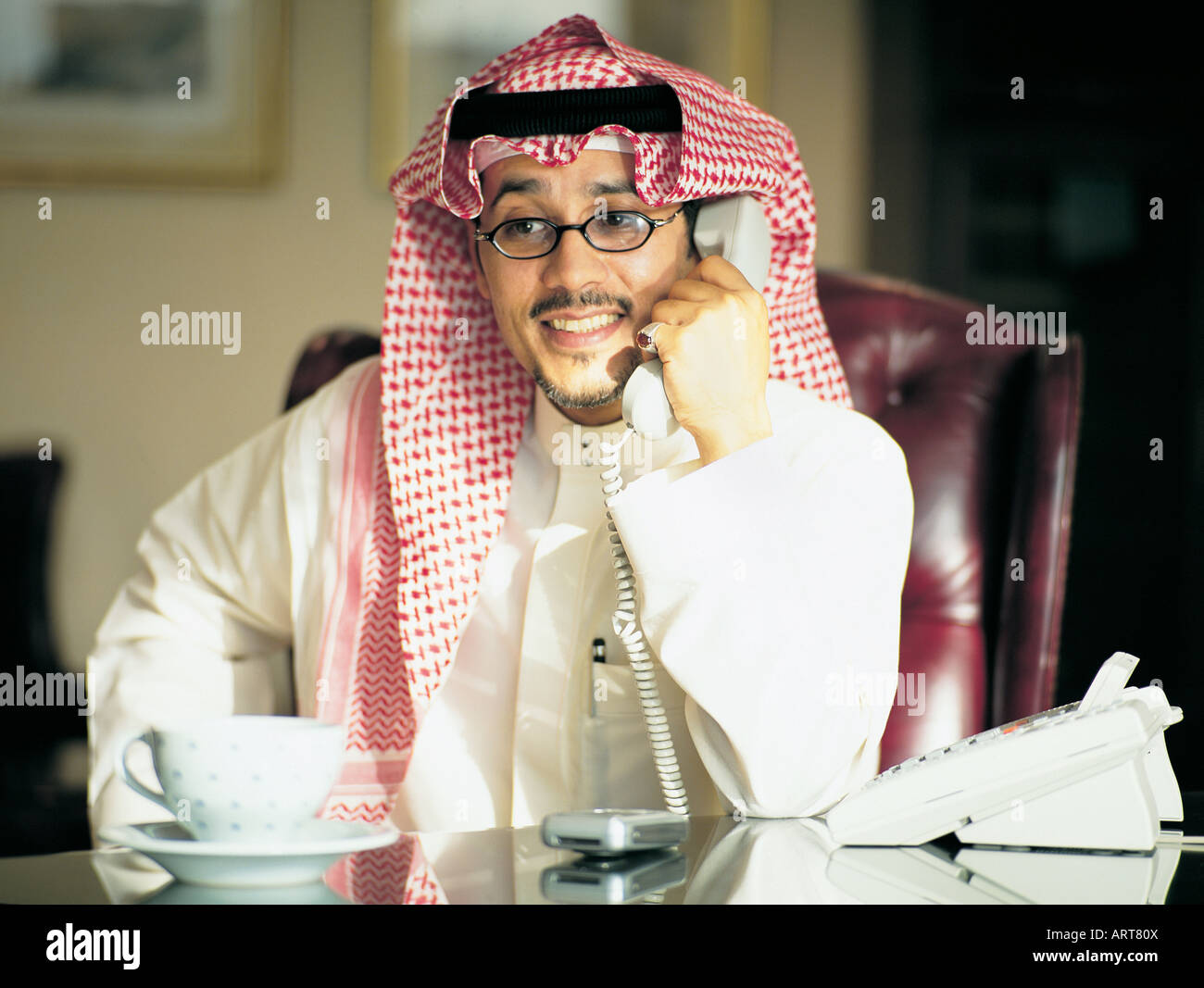 Saudi businessman using telephone in office Stock Photo - Alamy