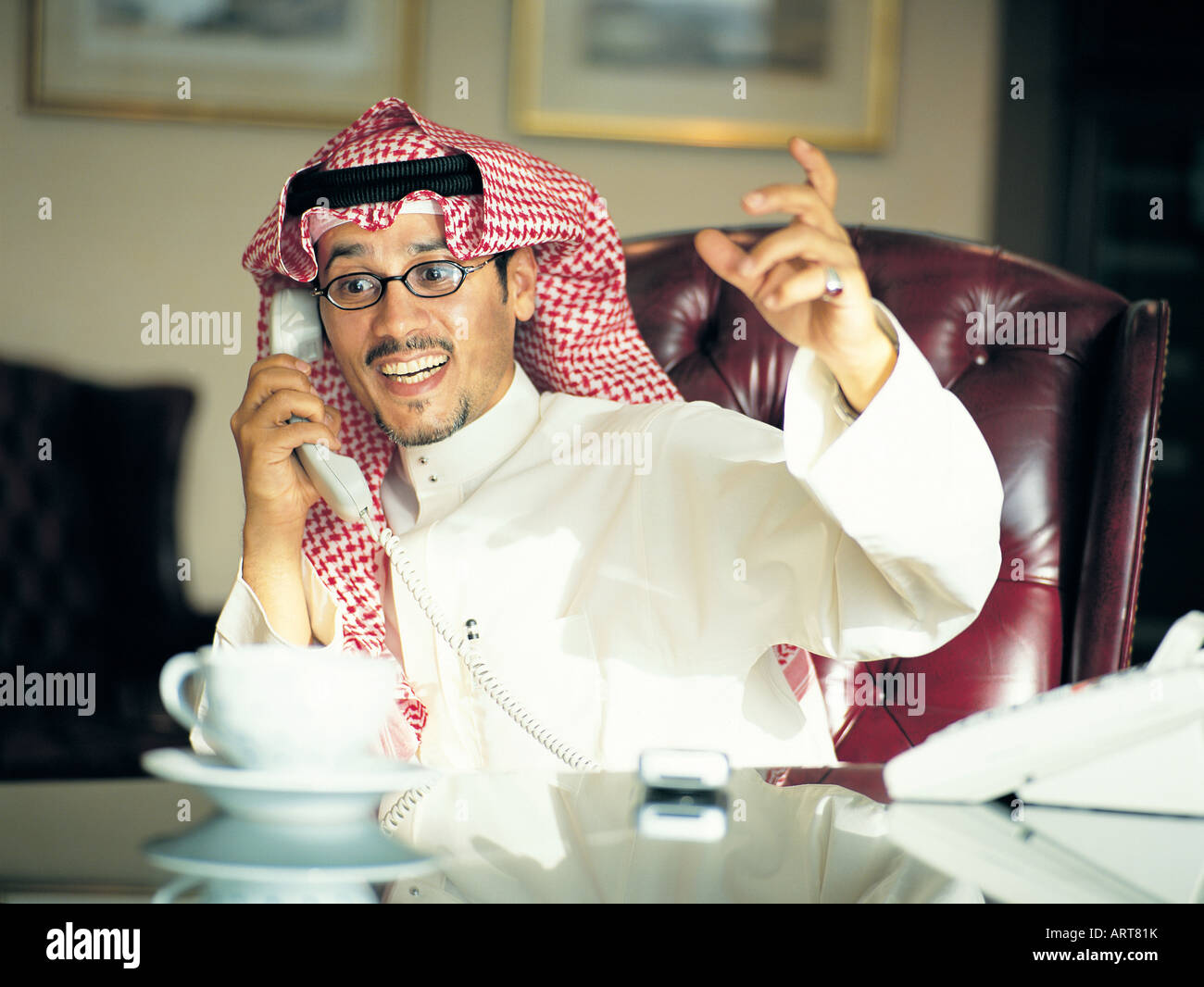 Excited Saudi businessman using telephone in office Stock Photo - Alamy
