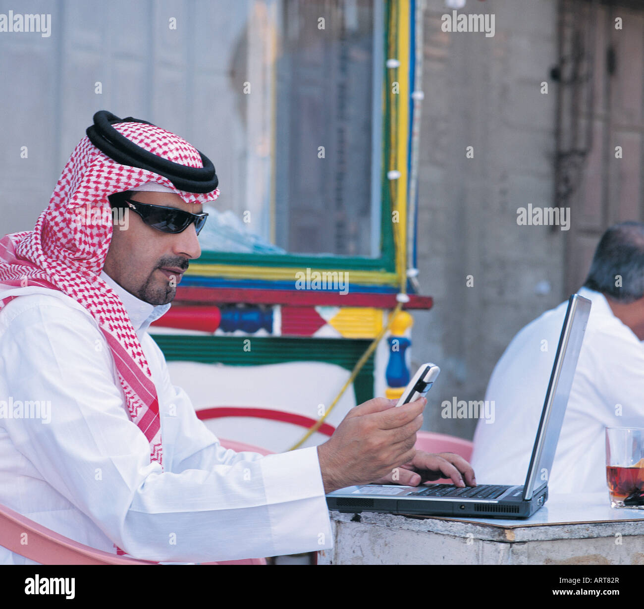 Saudi man using laptop and mobile phone in Old Town of Jeddah, Saudi ...