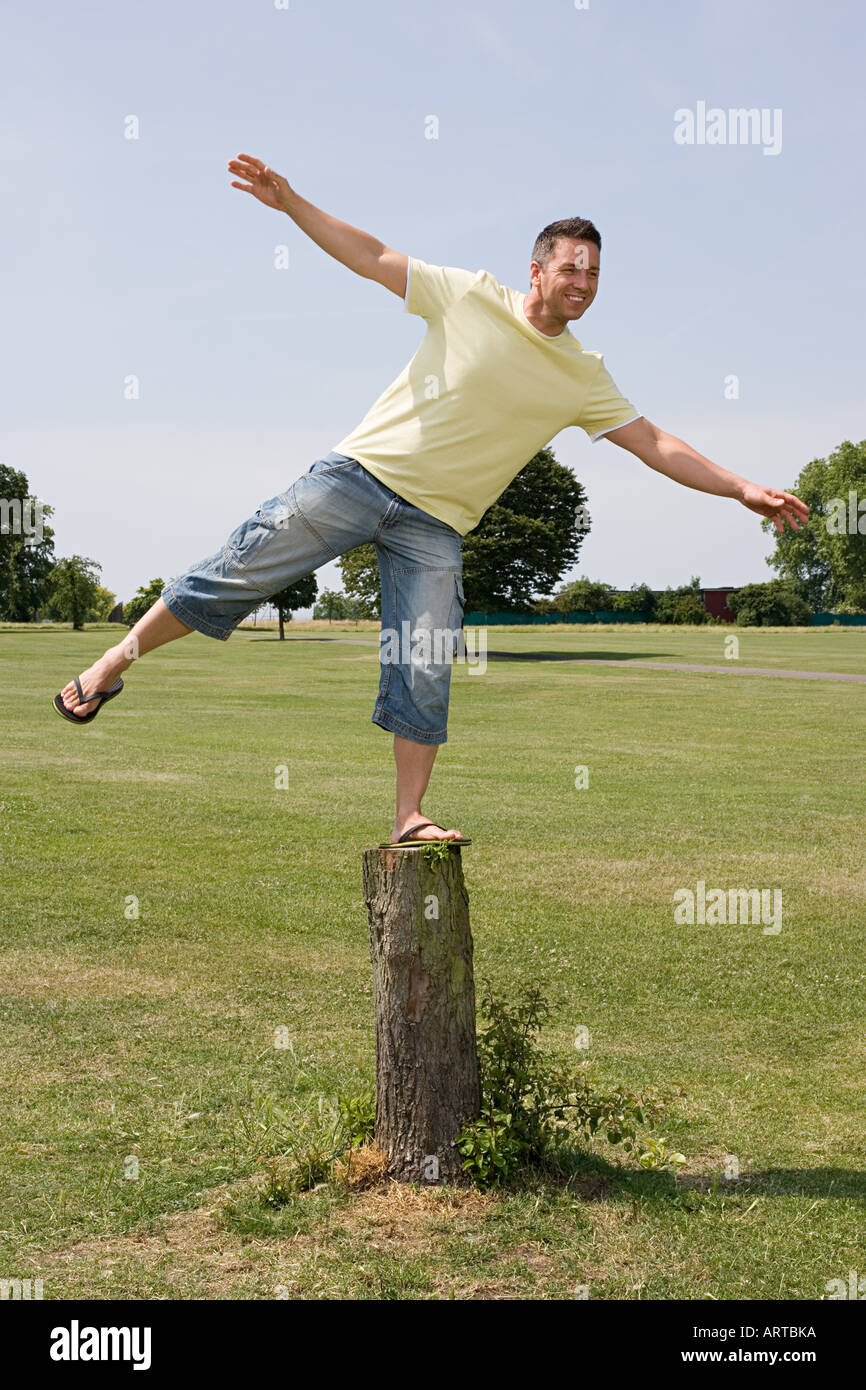 Man balancing on tree stump Stock Photo - Alamy