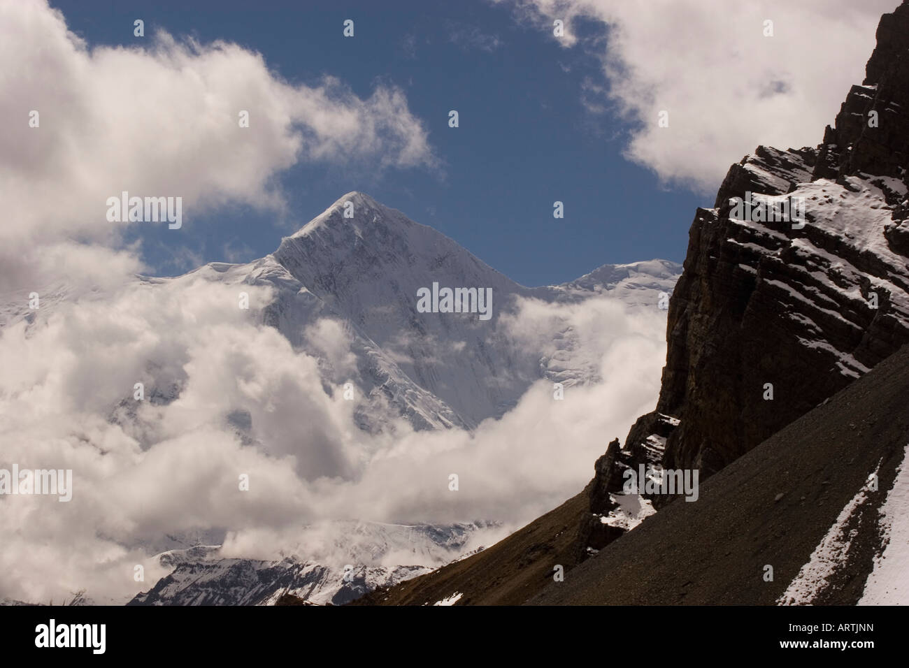 Peak peering through the clouds from high camp before the Thorung La on ...