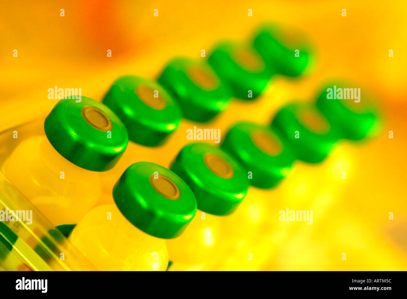 Rows of yellow vaccine vials with green tops Stock Photo - Alamy