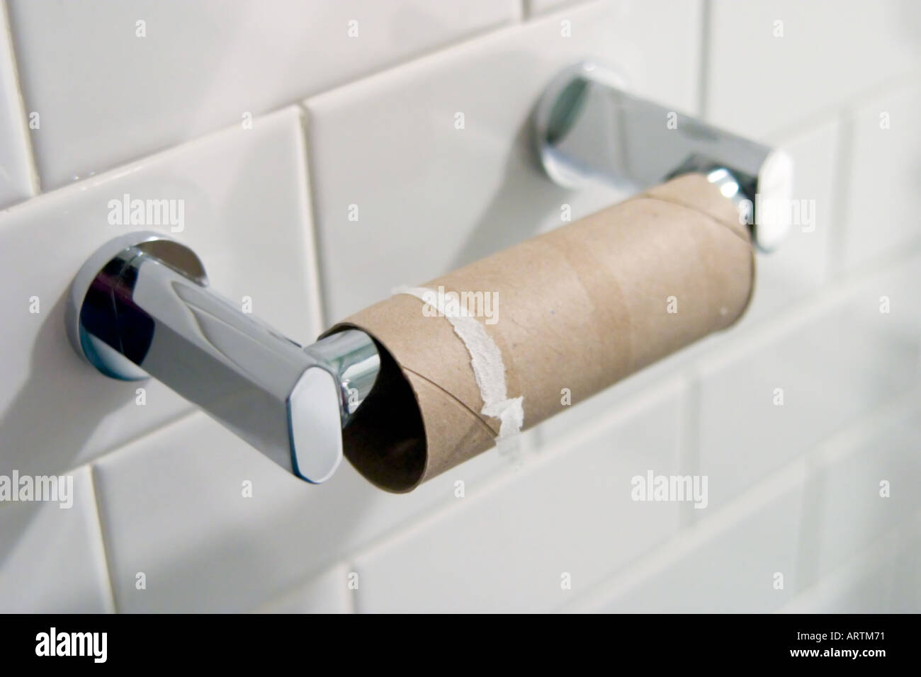 Empty cardboard roll of toilet paper against white tile background ...