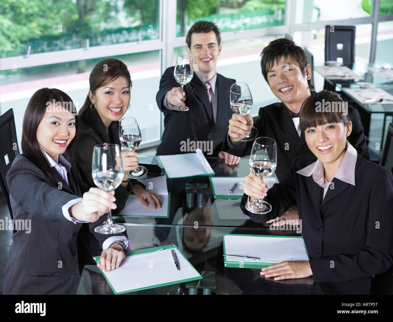 Group of business people raising glasses at restaurant table, smiling ...