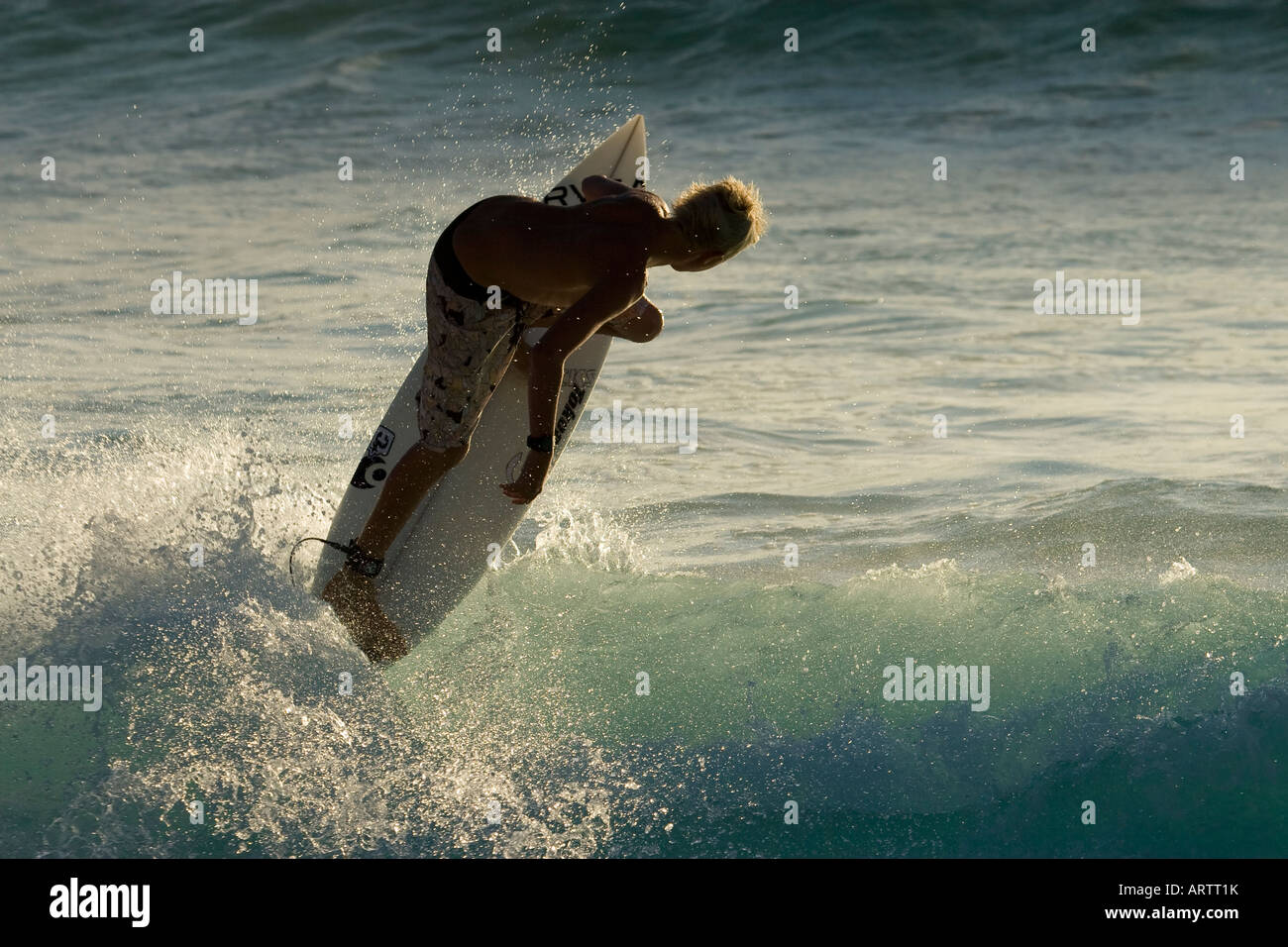 North Shore surfer catches air on backlit wave Stock Photo - Alamy