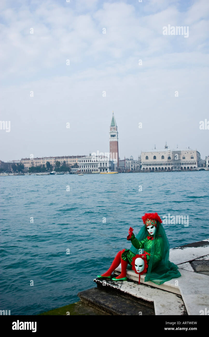 A girl dressed up in a carnival mask and costume sitting on the ...
