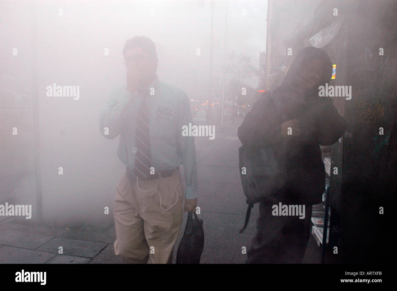 Pedestrians walk through smoke escaping from an underground fire at the ...