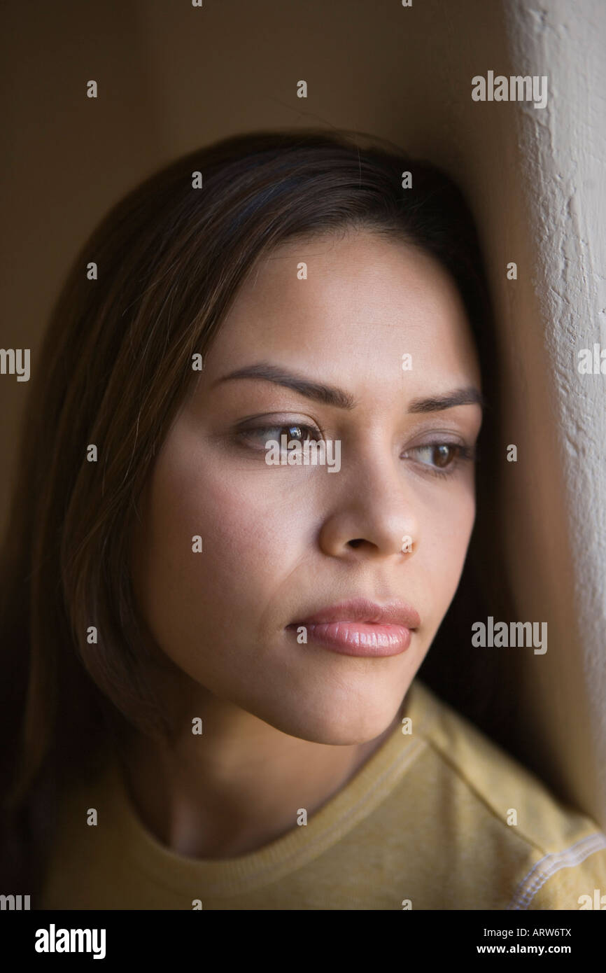 young woman looking towards window with an expression of longing Stock ...