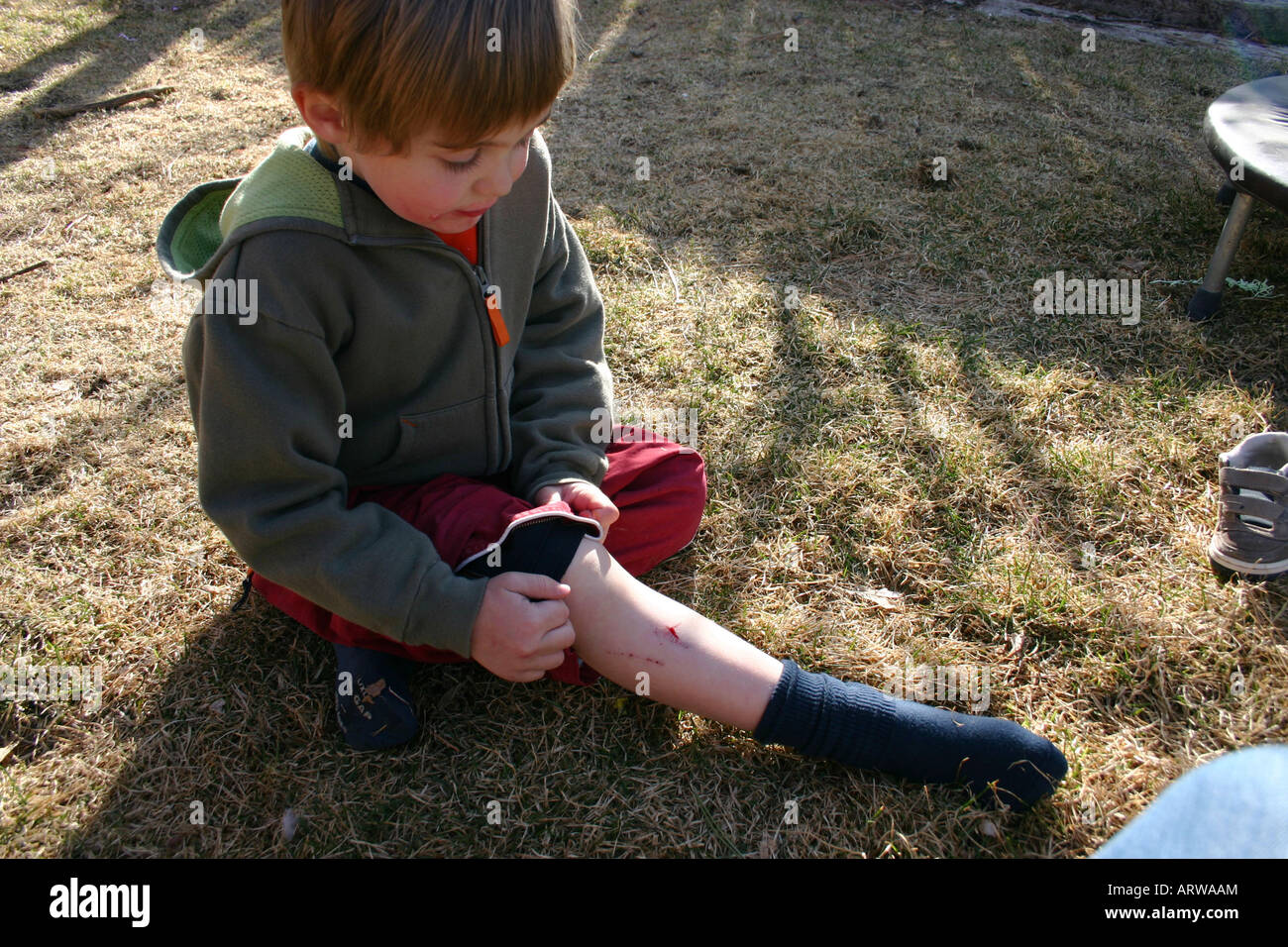 five year old child rolling up pants to look at scrape on leg Stock ...