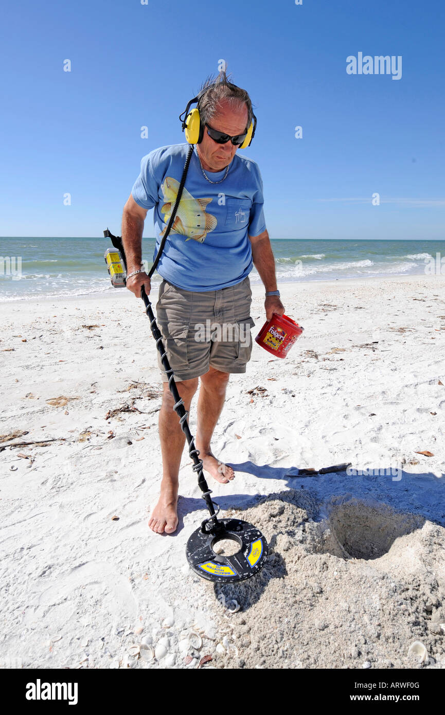 Senior male uses metal detector to find objects on a beach at Naples ...