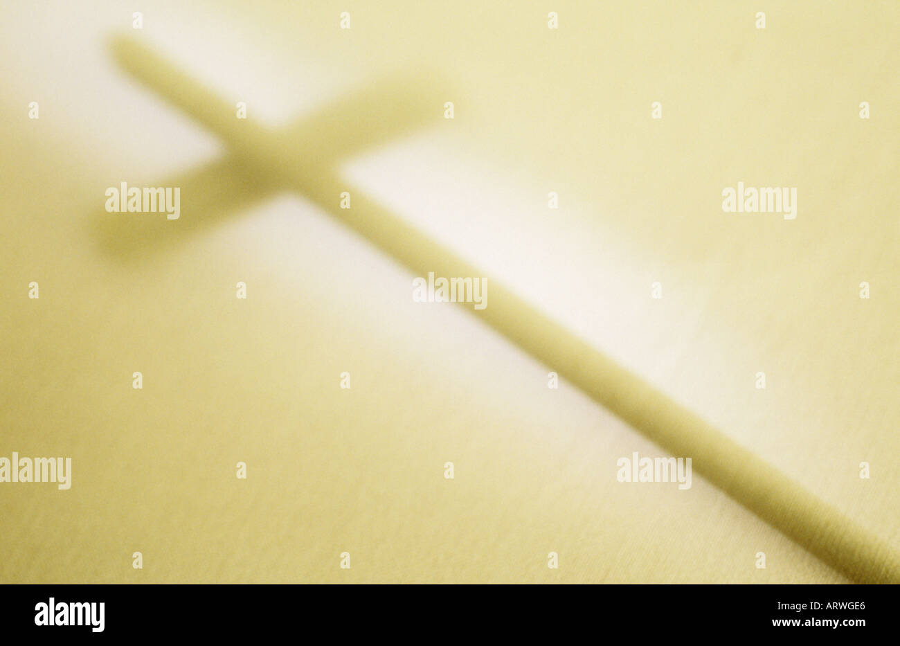 Light shadow of a crucifix cast in a shaft of light on a white surface ...