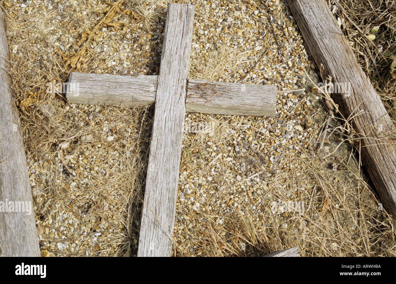 Simple wooden cross which has collapsed onto a dry dusty grave of ...
