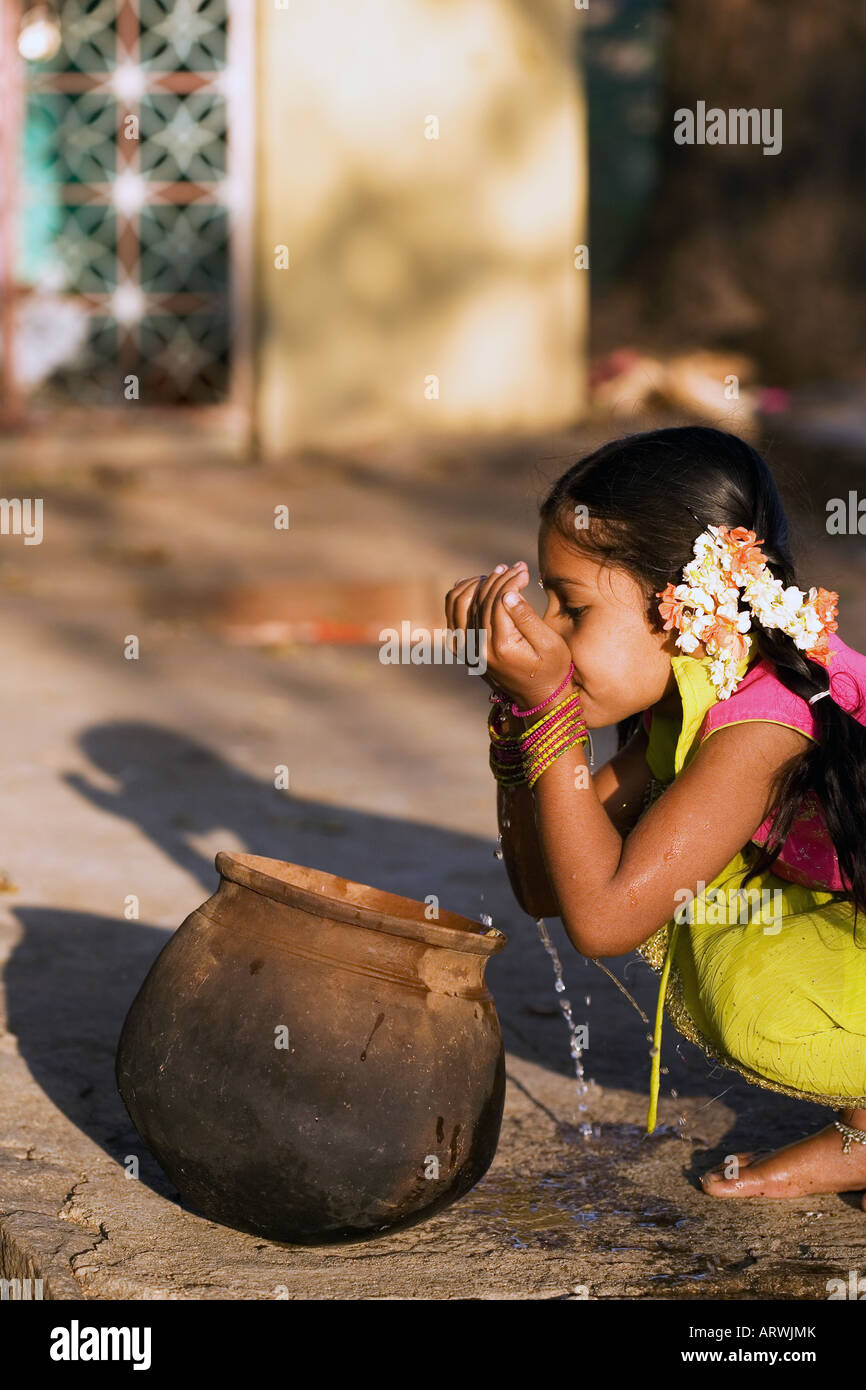 Indian girl drinking fresh water from a clay pot at a rural indian hand ...