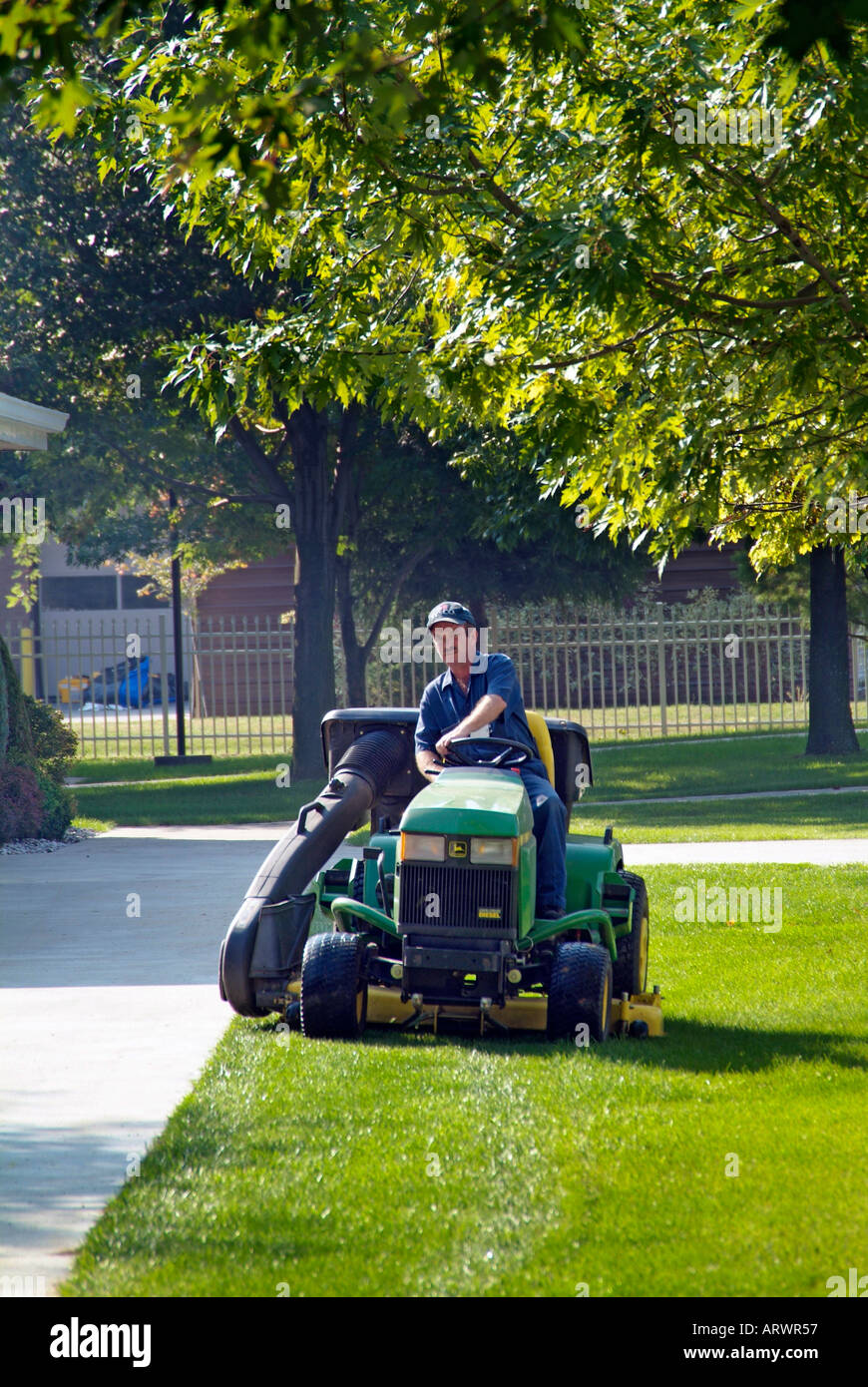 Worker mows lawn on a riding lawn mowing tractor Stock Photo - Alamy
