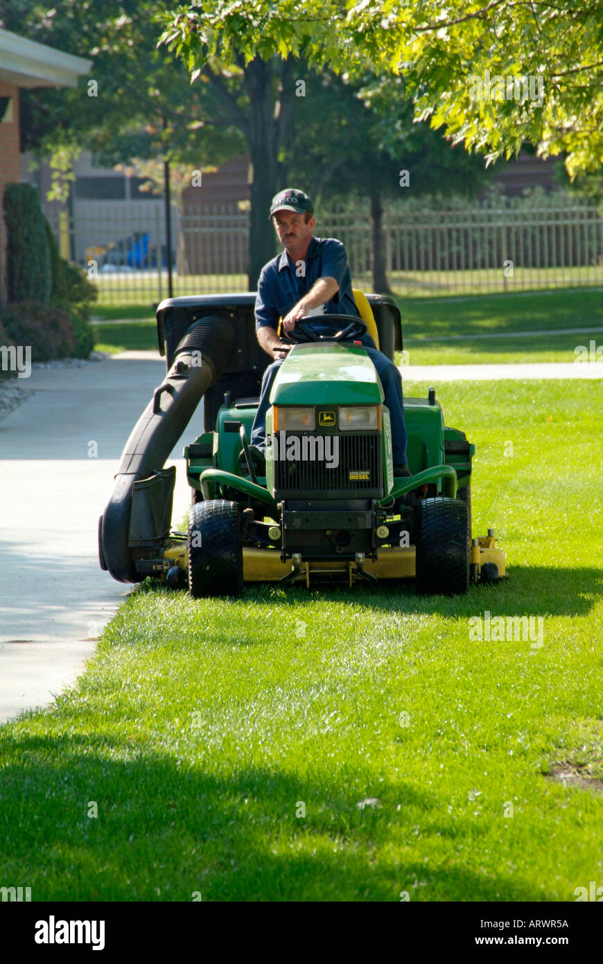 Worker mows lawn on a riding lawn mowing tractor Stock Photo - Alamy