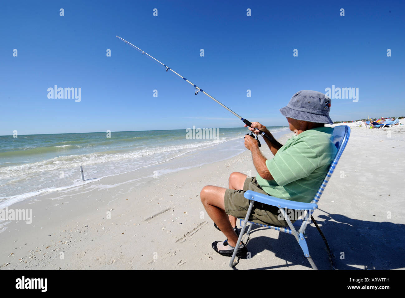 Senior man fishing for recreation in the Gulf of Mexico at Naples ...