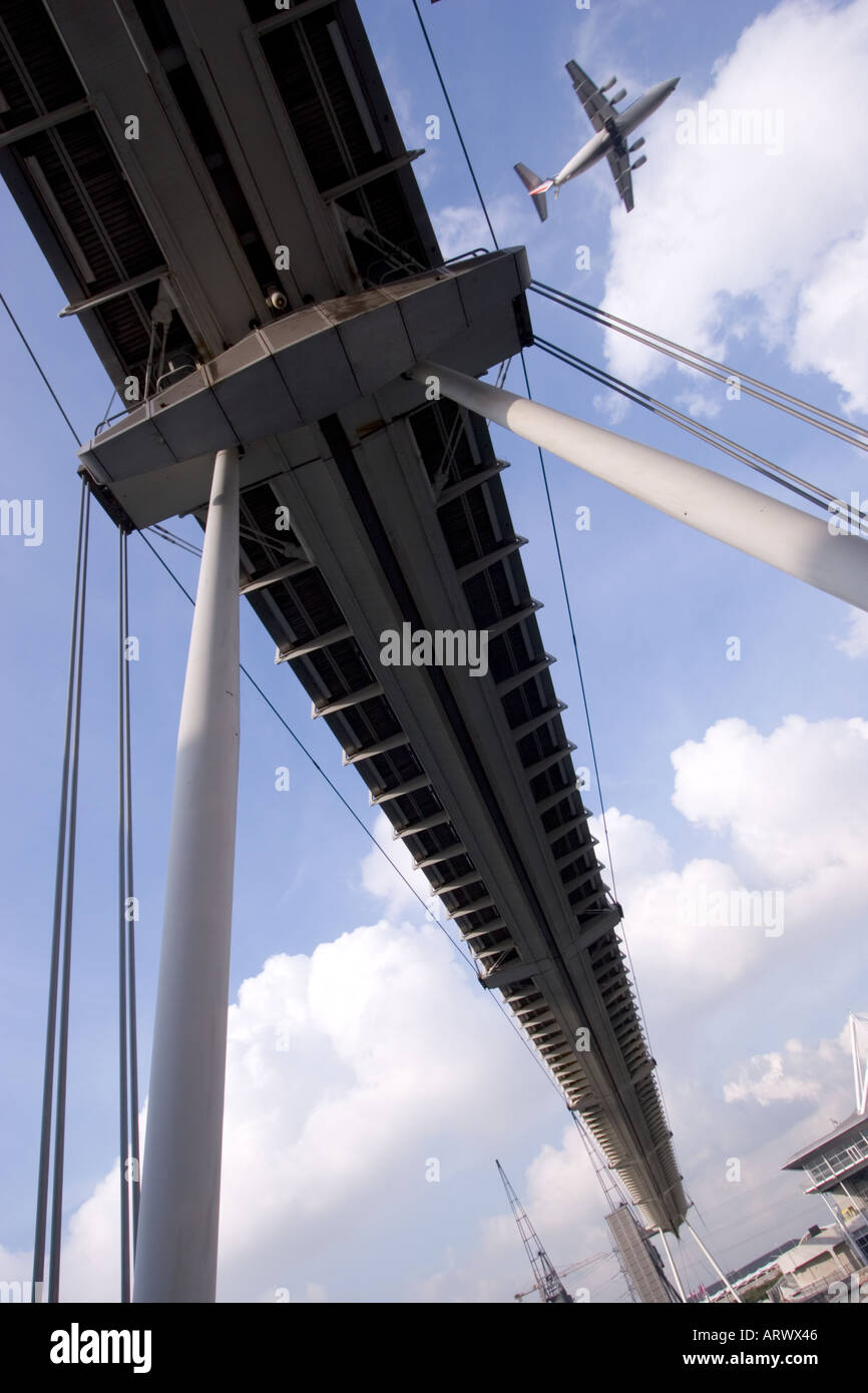 Royal Victoria dock footbridge with aircraft low flying over on ...