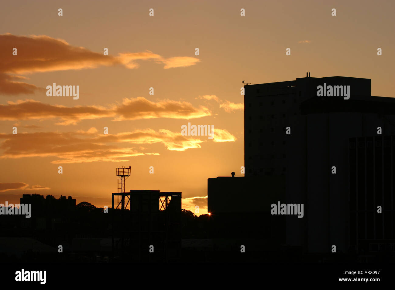 The sun setting behind an industrial skyline Stock Photo - Alamy