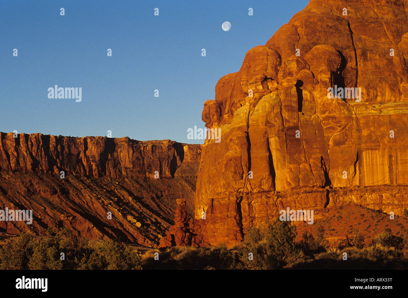 Golden cliffs lit by sunrise with moon, Arches National Park, Utah ...