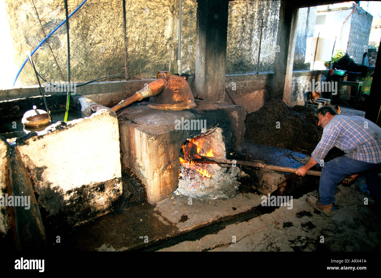 greece crete a man making raki from the grape skins using a traditional ...