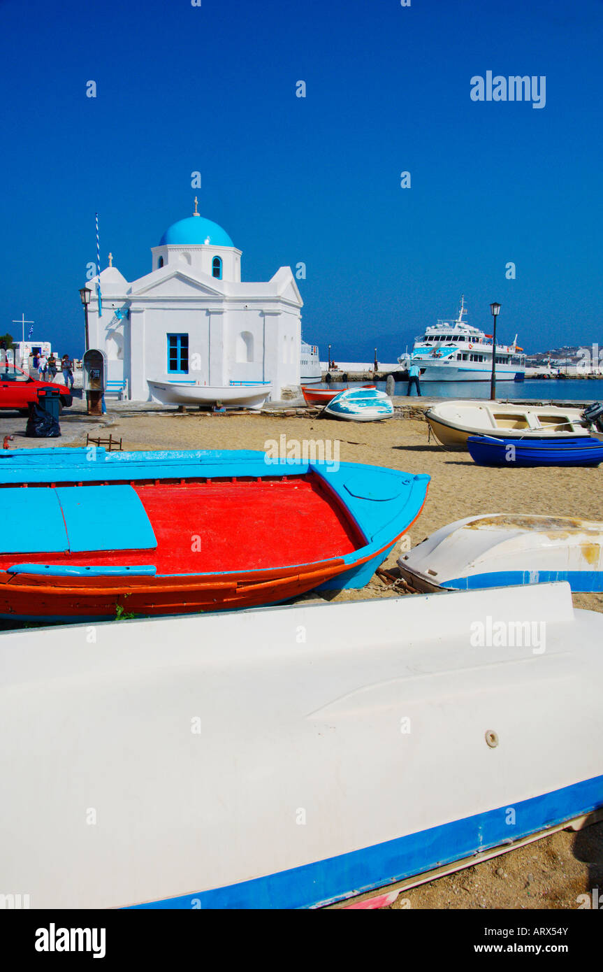 A small white church with colorful fishing boats at the port of Hora on ...