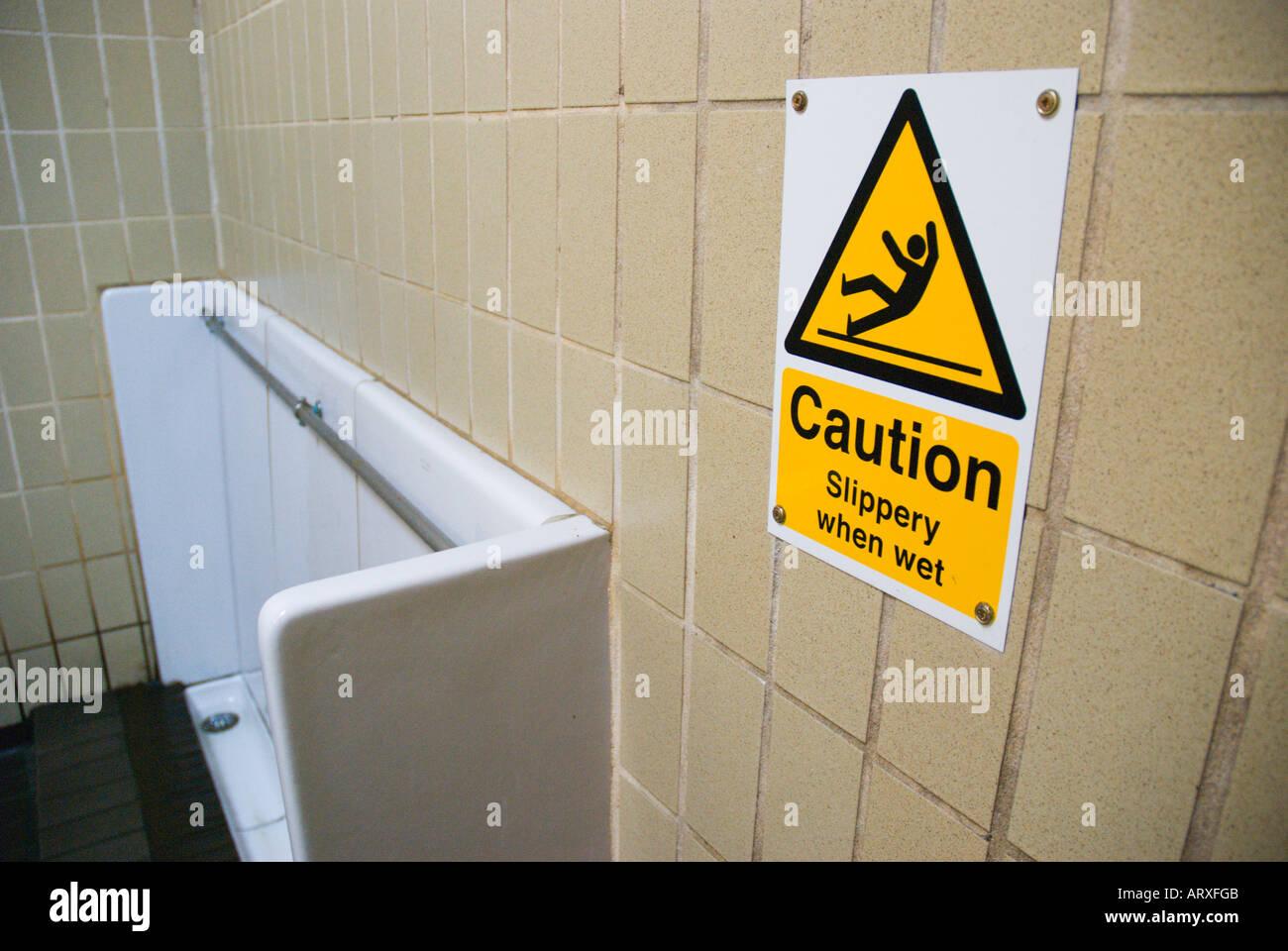 Slippery when wet warning sign in men's lavatories in UK Stock Photo ...
