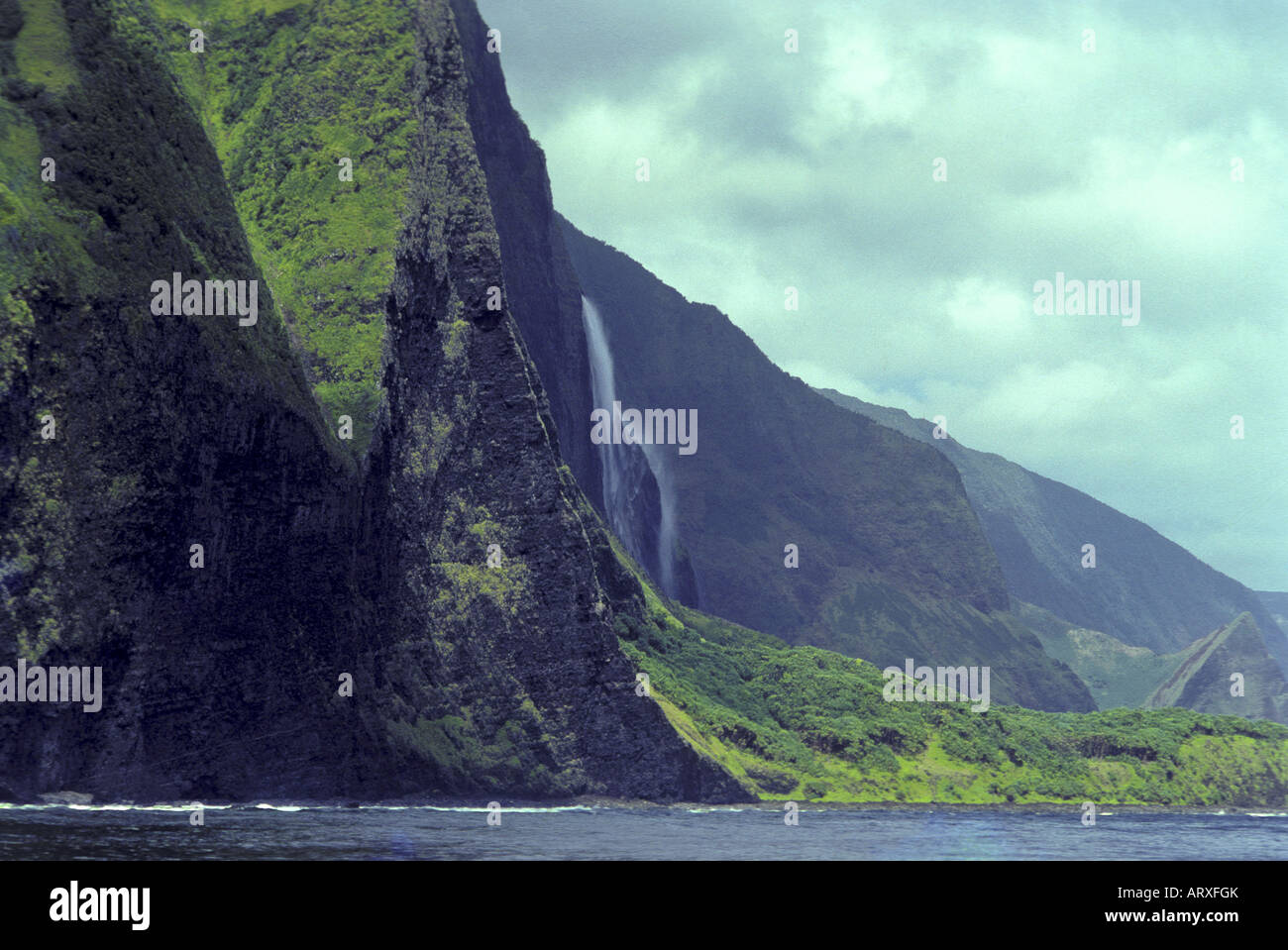 A spectacular waterfall cascades down the secluded lush mountains near ...