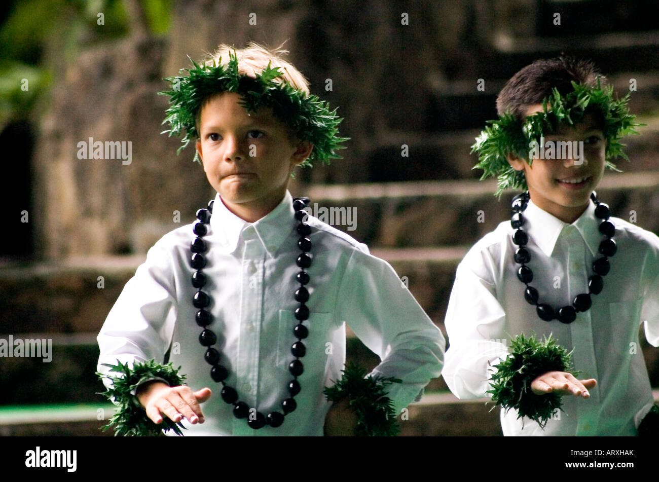 Two boys in white shirts and kukui nut leis dancing a modern hula Stock ...