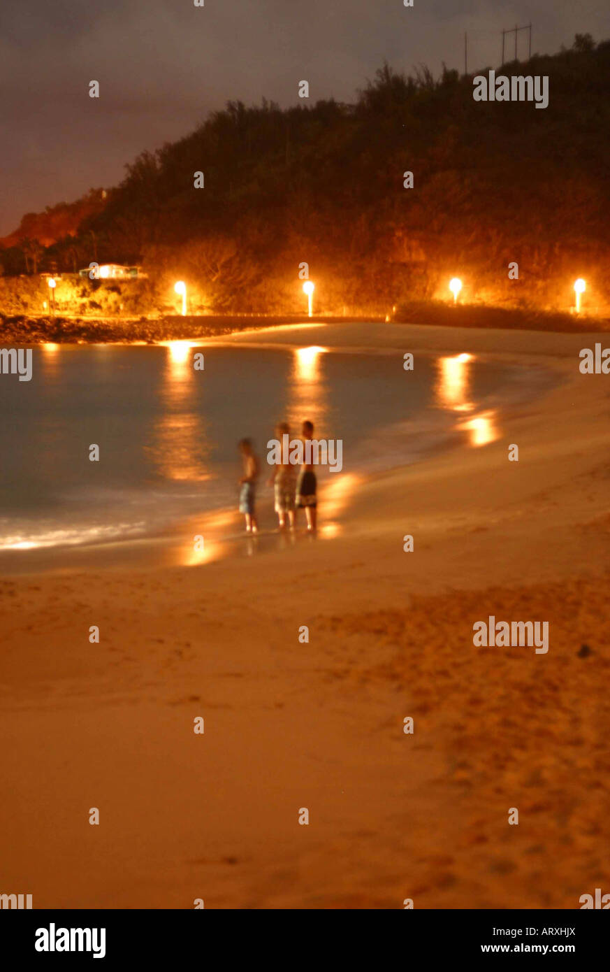 Three boys stand on the beach after sundown. Waimea bay on the North ...