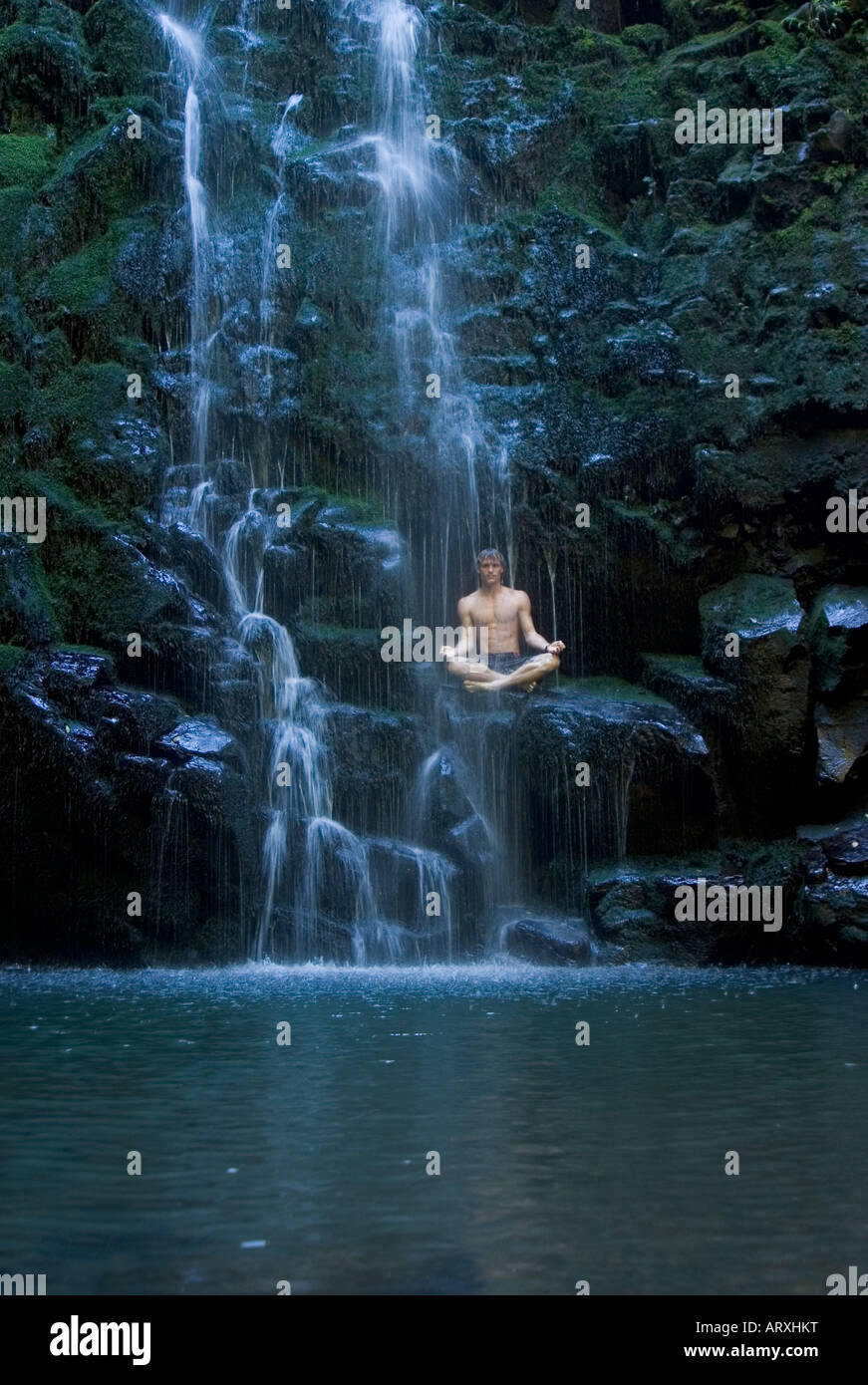 Man sitting in meditation position relaxes under a waterfall Stock ...