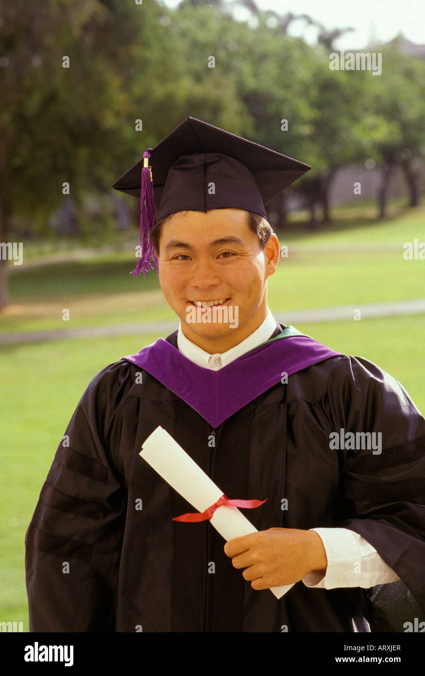 Young man proudly displaying his diploma at college graduation from ...