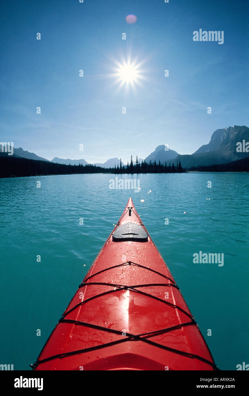 View looking over the bow of a red kayak in a lake with sunburst ...
