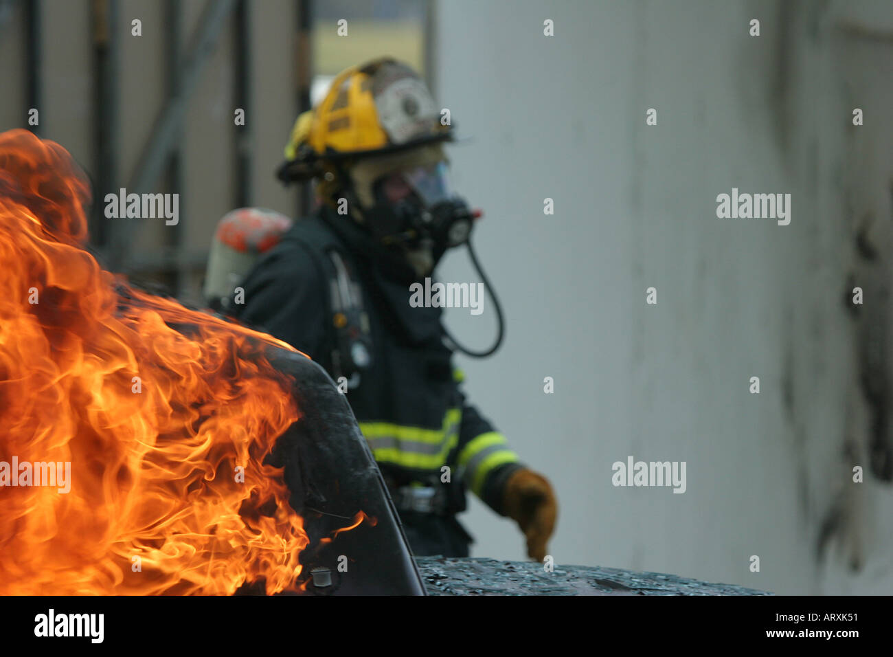Fire fighter in the background walking around a car fire investigating ...