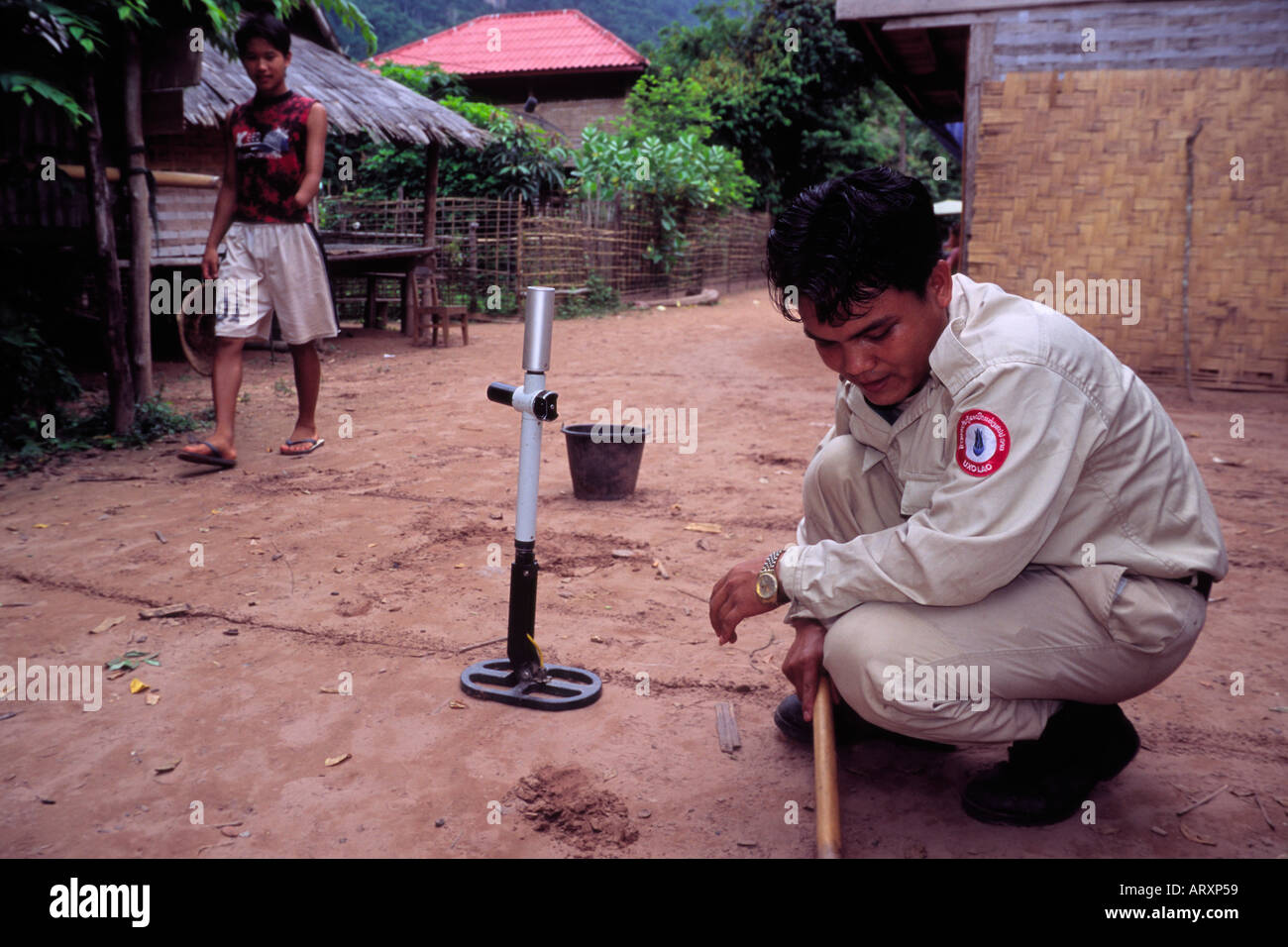An UXO officer searching for unexploded ordnance with the boy in the ...