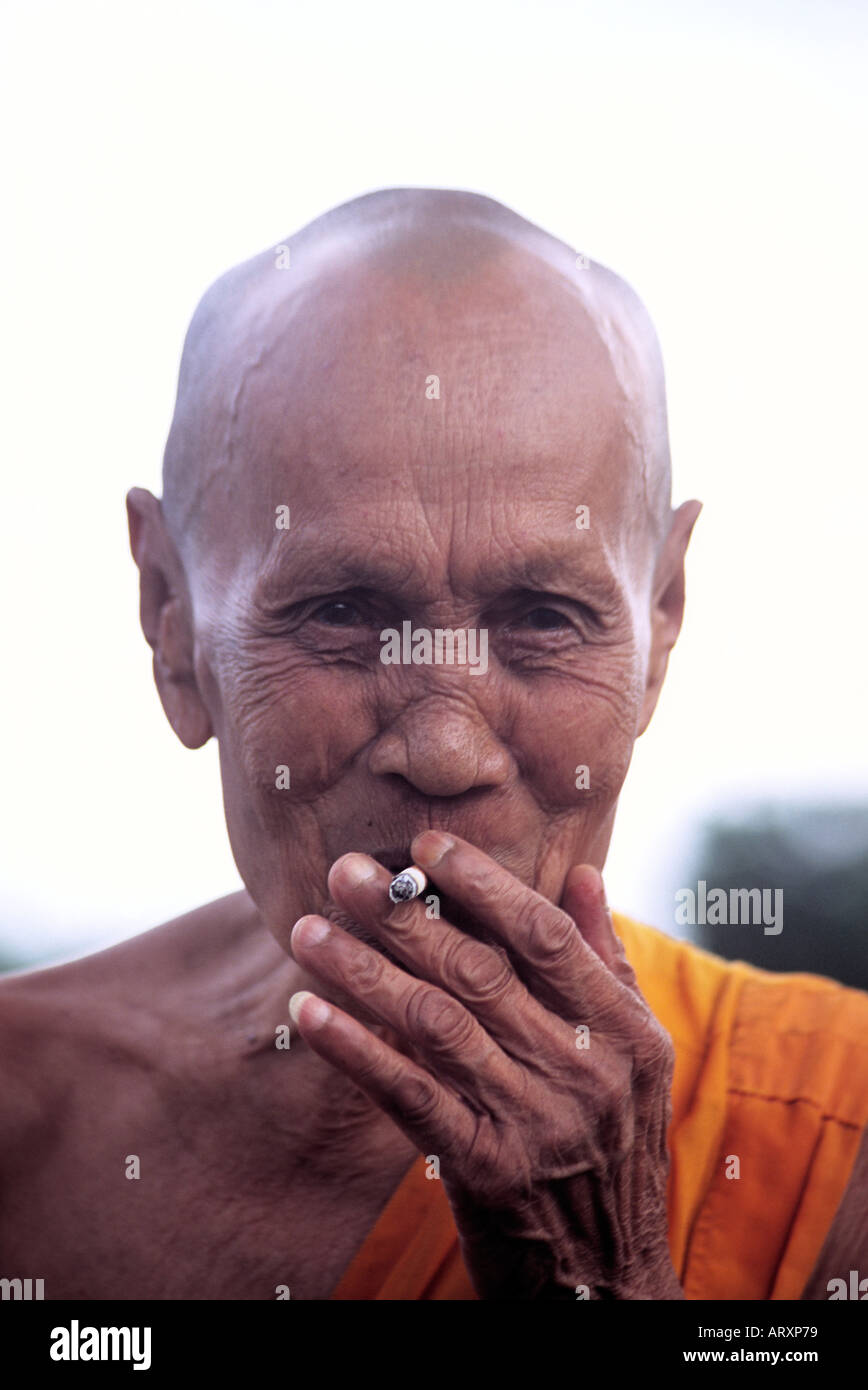 An elderly laotian buddhist monk smokin a cigarette in Luang Prabang ...