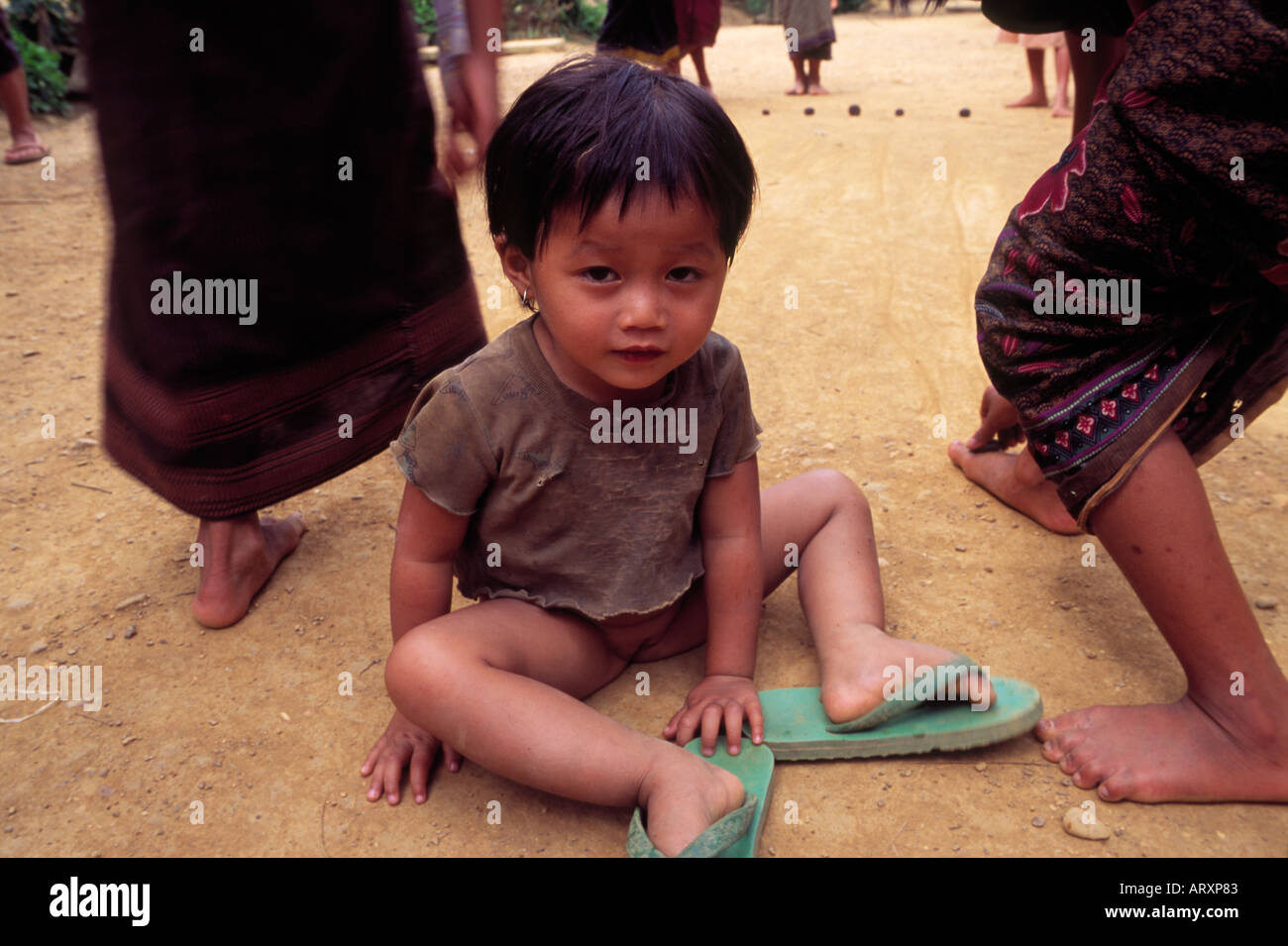A young laotian girl sitting on a ground in front of the playing ...