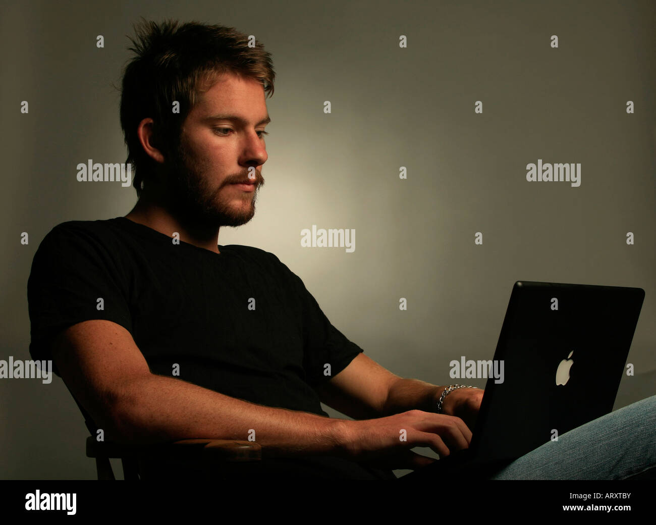 Fashionable young man in jeans with computer Stock Photo - Alamy