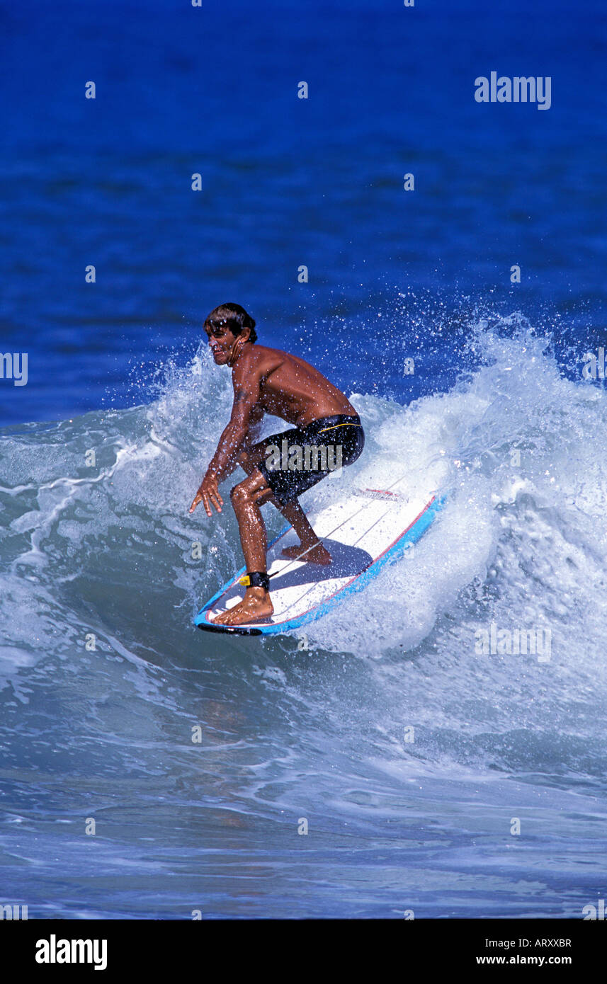 A tanned young surfer rides a choppy white wave at a Maui beach Stock ...