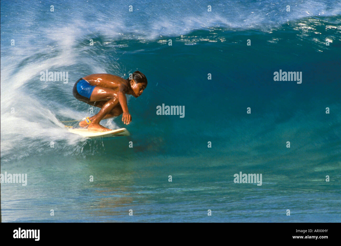 Local boy surfing on a bright blue wave at ehukai beach on Oahu's ...