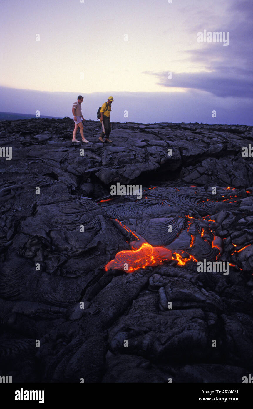 Two men on a lava field viewing molten lava, Volcanoes National park ...