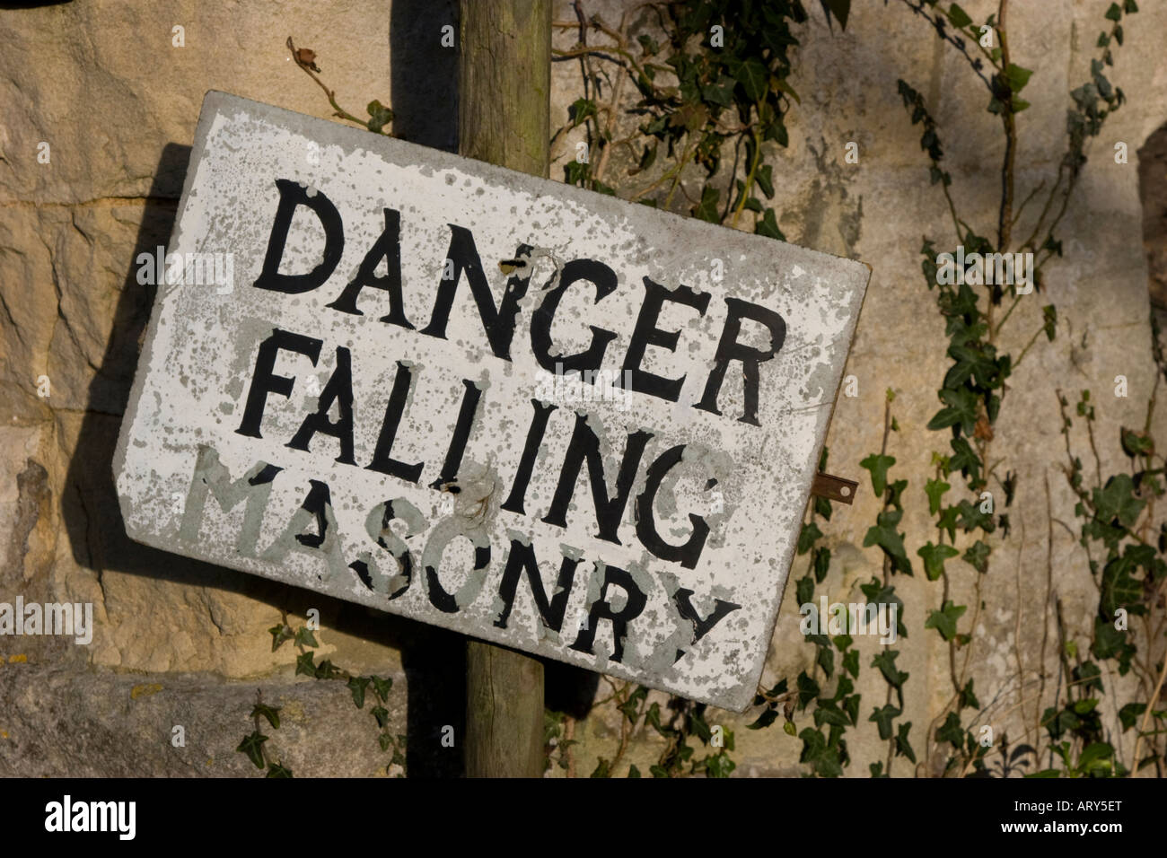 Lop-sided sign warning of: Danger, falling masonry Stock Photo - Alamy