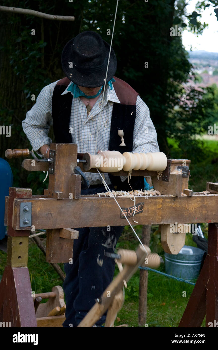 Craftsman working on a manually powered wooden lathe at a forest ...