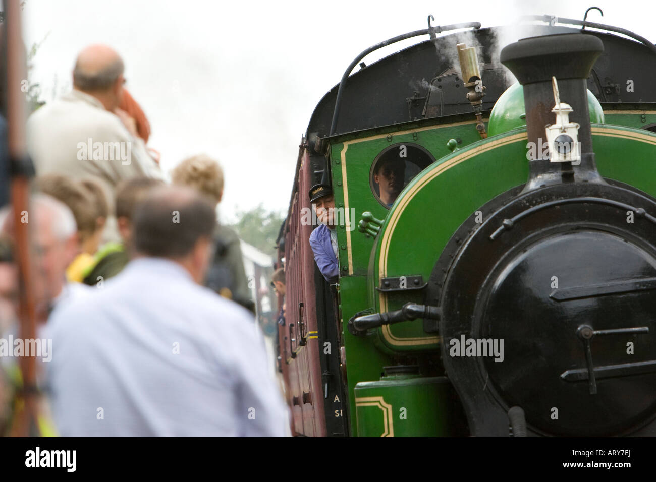 Driver leaning out of the cab as his steam locomotive pulls into the ...