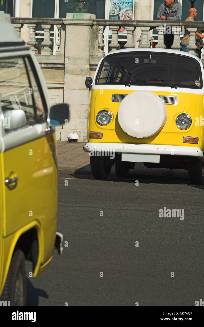 Two yellow Volkswagen VW camper vans facing each other across the road ...