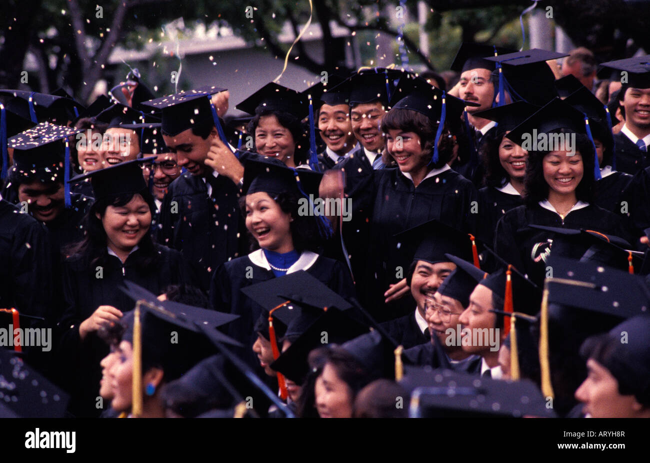 Group celebrating at their graduation ceremony with confetti in the air ...